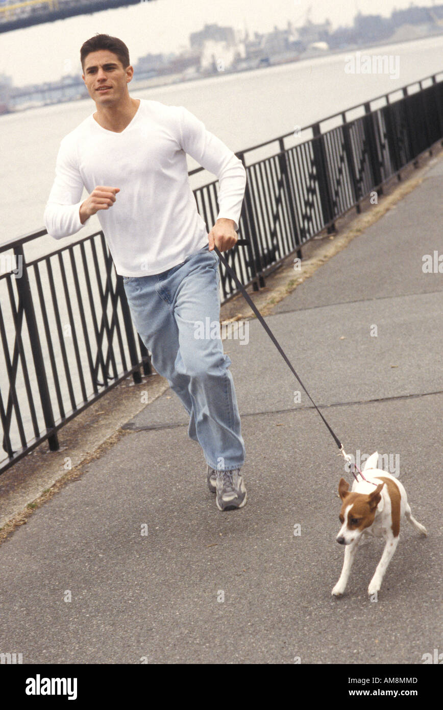 Man running with dog by railings Stock Photo - Alamy