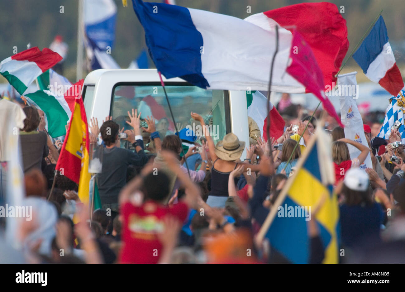 Pope Benedictus XVI in the Popemobile amidst a crowd of flag waving ...