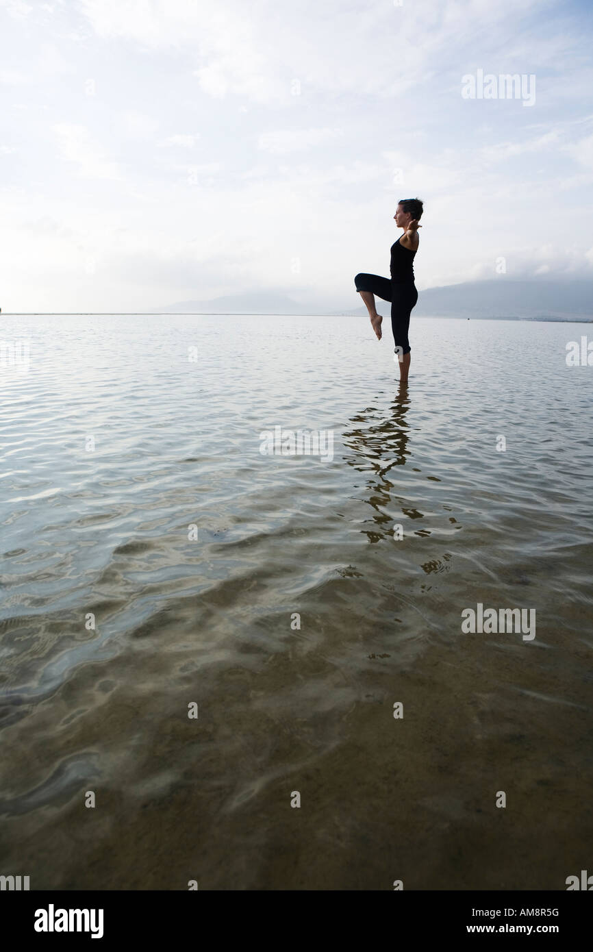 Woman in a balance pose standing in water doing Yoga Stock Photo - Alamy