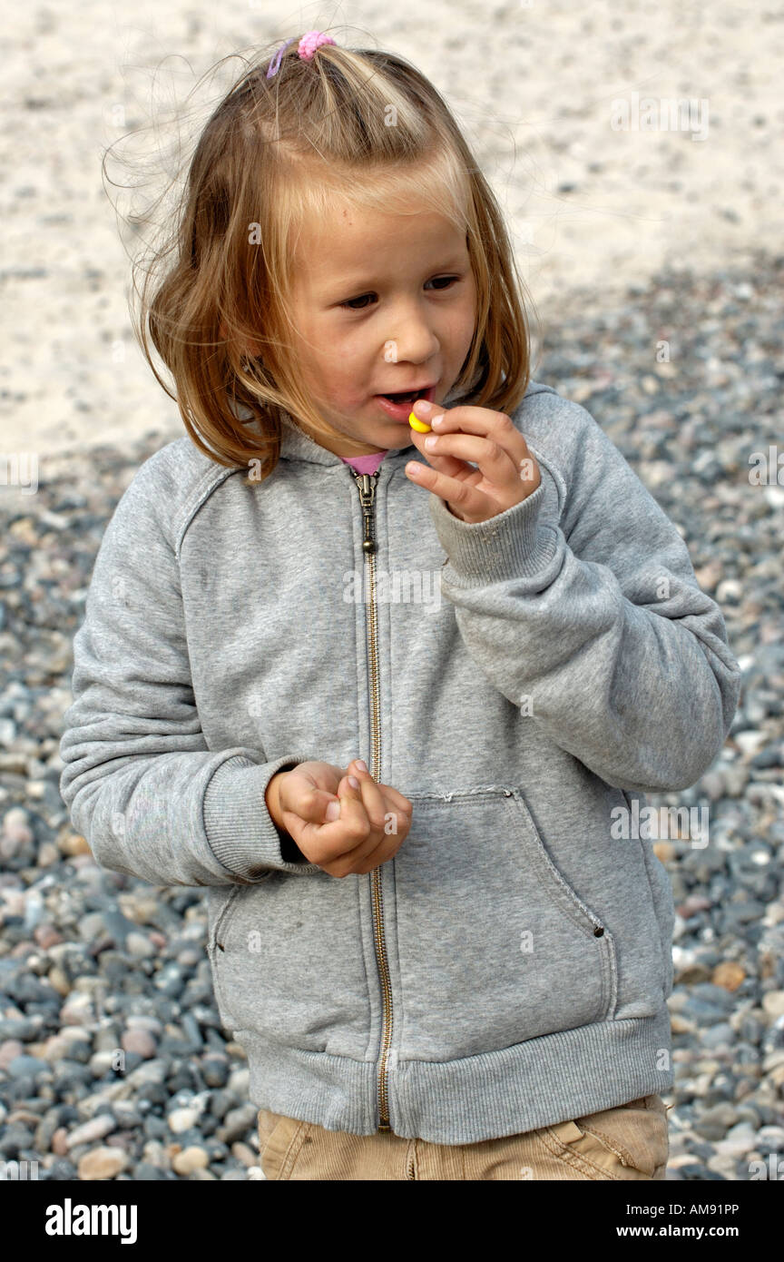 Young girl aged five eating smarties outside Stock Photo - Alamy