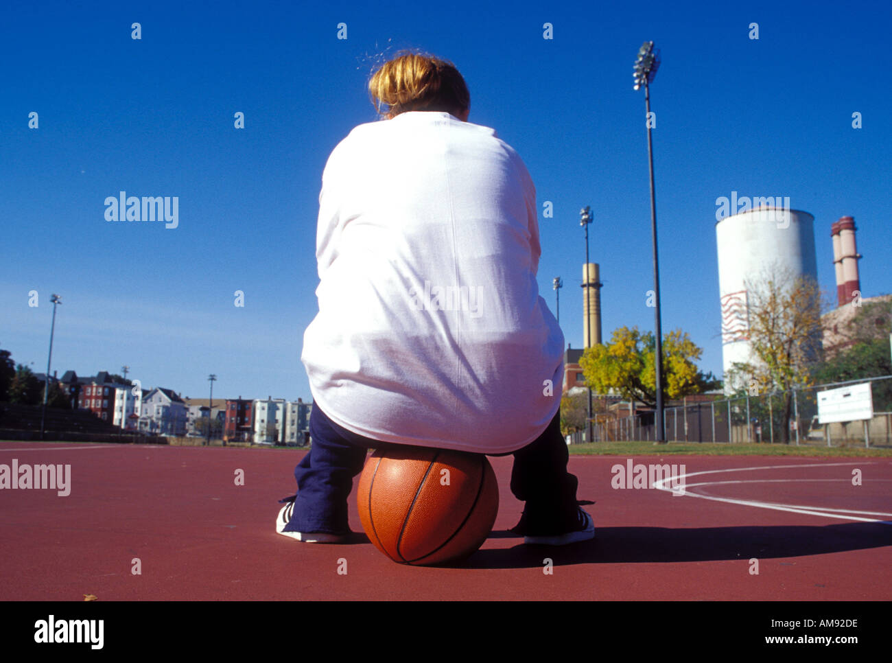 Girl Sitting on Basketball Stock Photo - Alamy