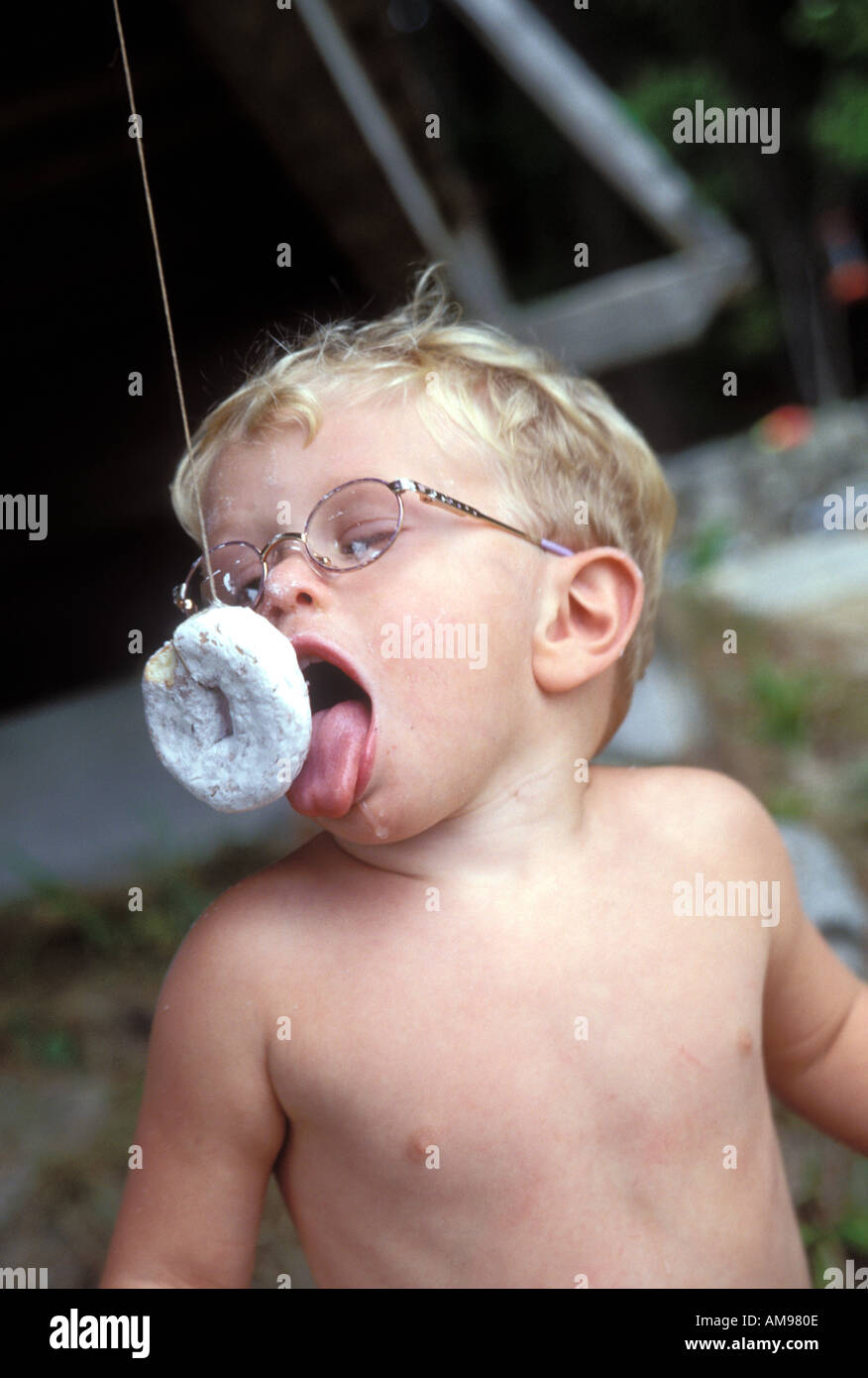 Boy Eating Donut on String Stock Photo - Alamy