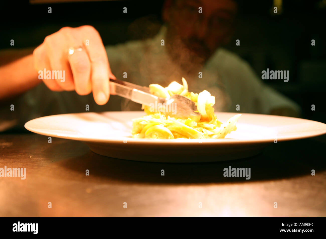 A chef places food under a hot light Stock Photo - Alamy