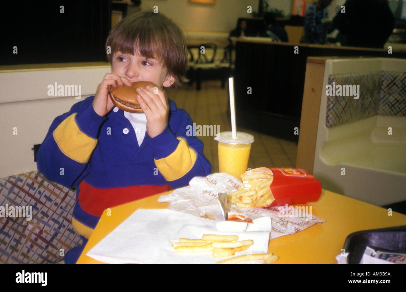 Young child eating hamburger in fast food restaurant Stock Photo - Alamy