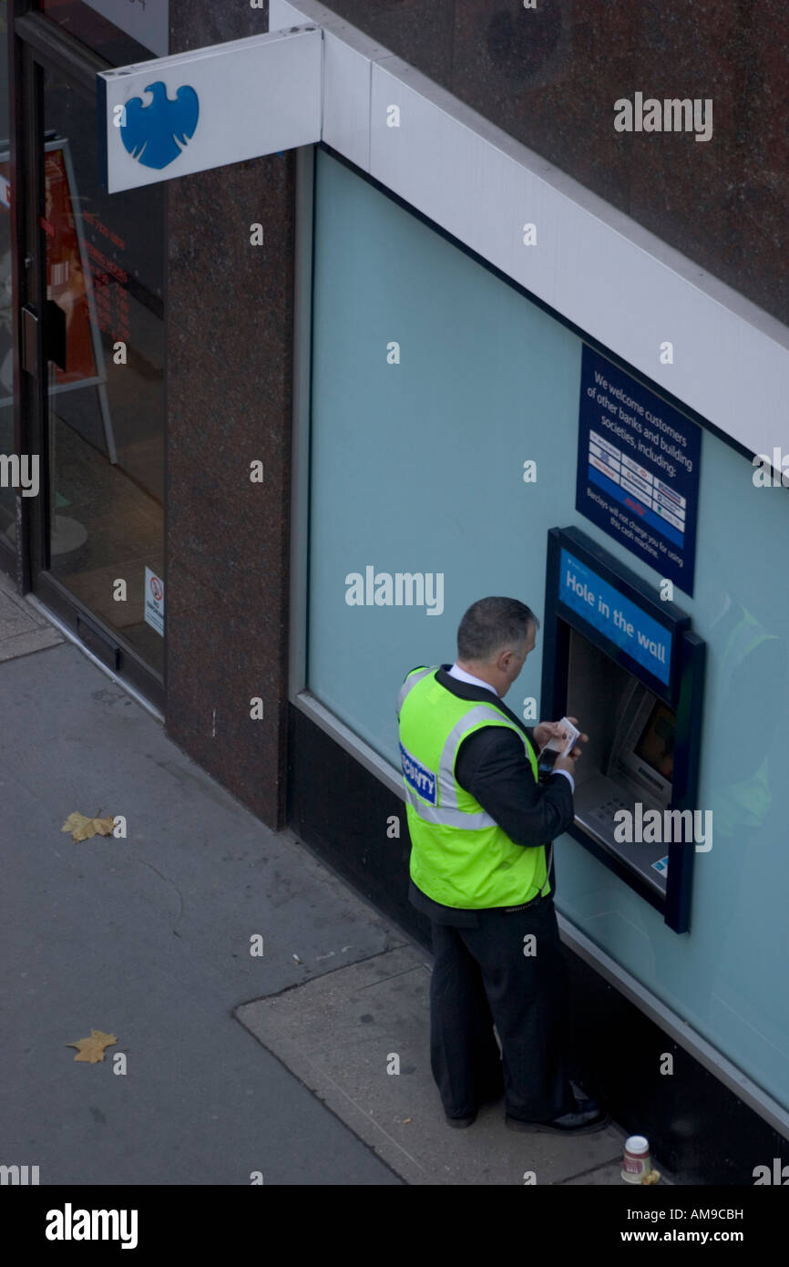 Security guard taking money from cash till atm hole in the wall machine ...
