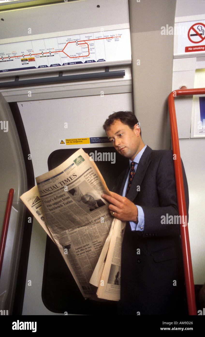 Commuter reading financial Times on underground Stock Photo - Alamy