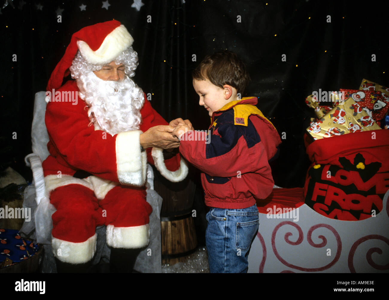 father Christmas giving Christmas present to young boy in Santas grotto ...