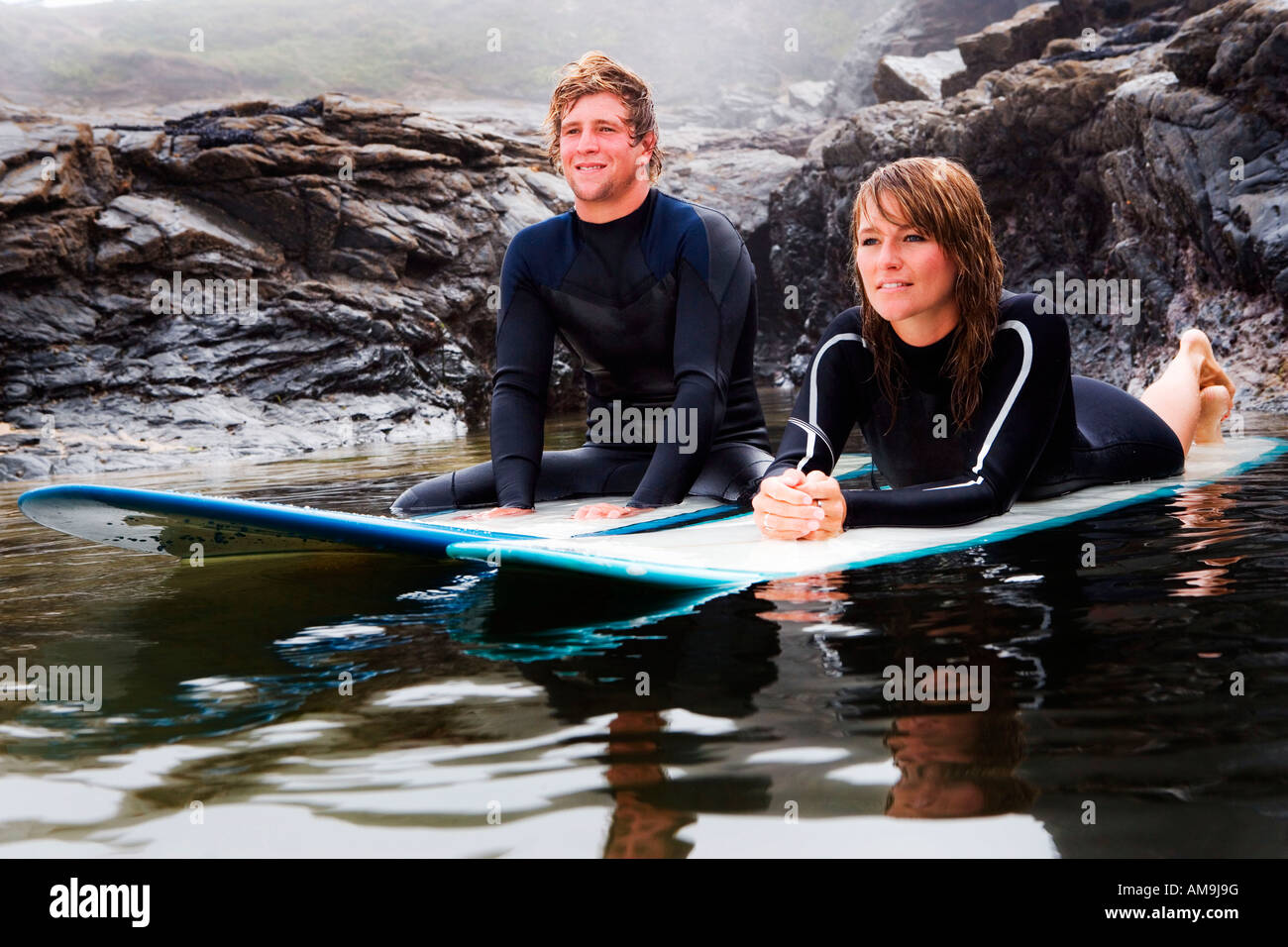 Couple lying on surfboards in the water smiling Stock Photo - Alamy