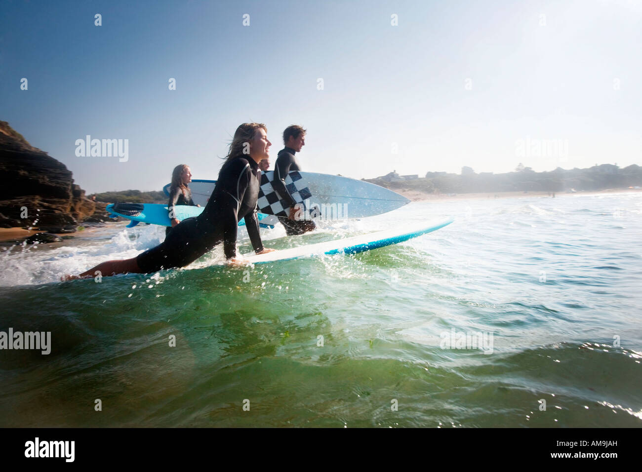 Four people going out to surf smiling Stock Photo - Alamy