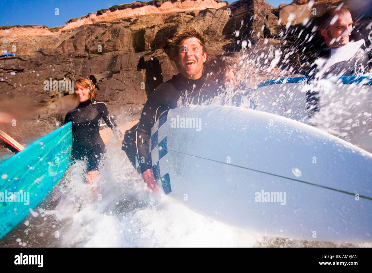 Four people running into the water with surfboards smiling Stock Photo ...