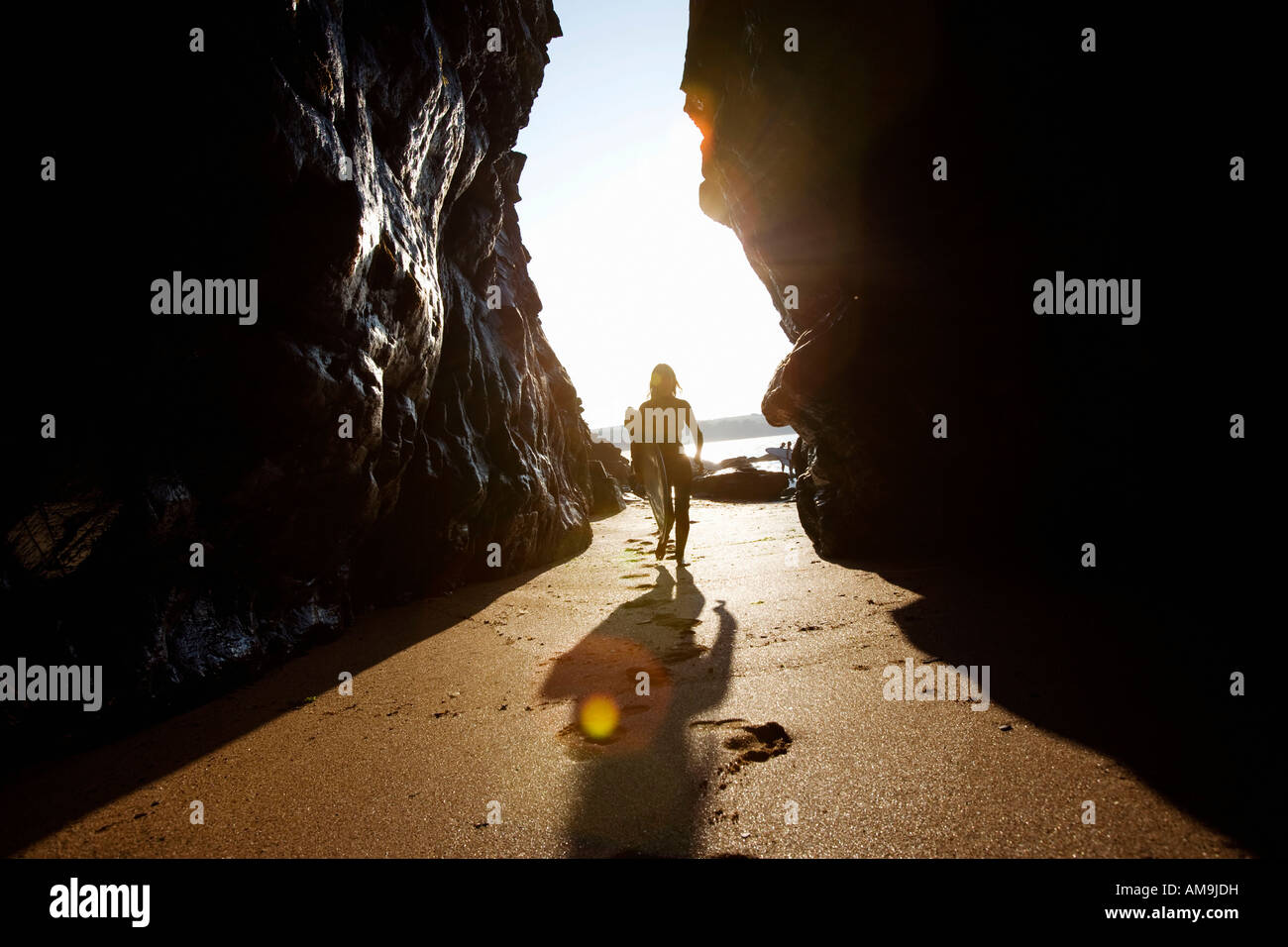 Woman carrying surfboard through large rocks Stock Photo - Alamy