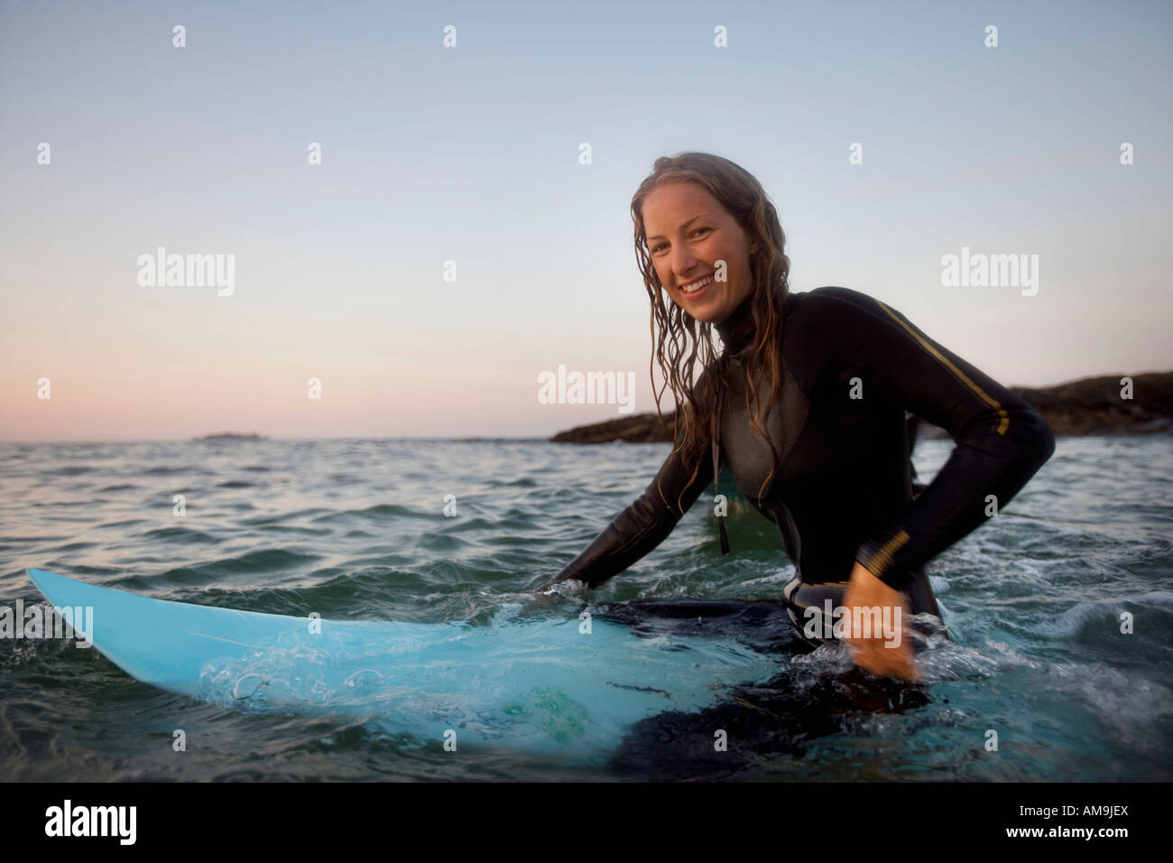 Woman sitting on surfboard in the water smiling Stock Photo - Alamy
