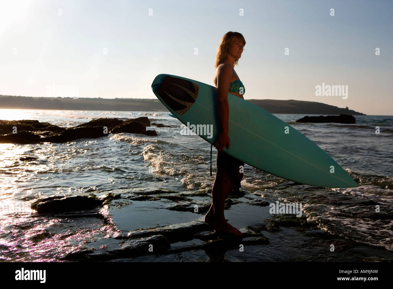Woman standing in shallow water with surfboard Stock Photo - Alamy