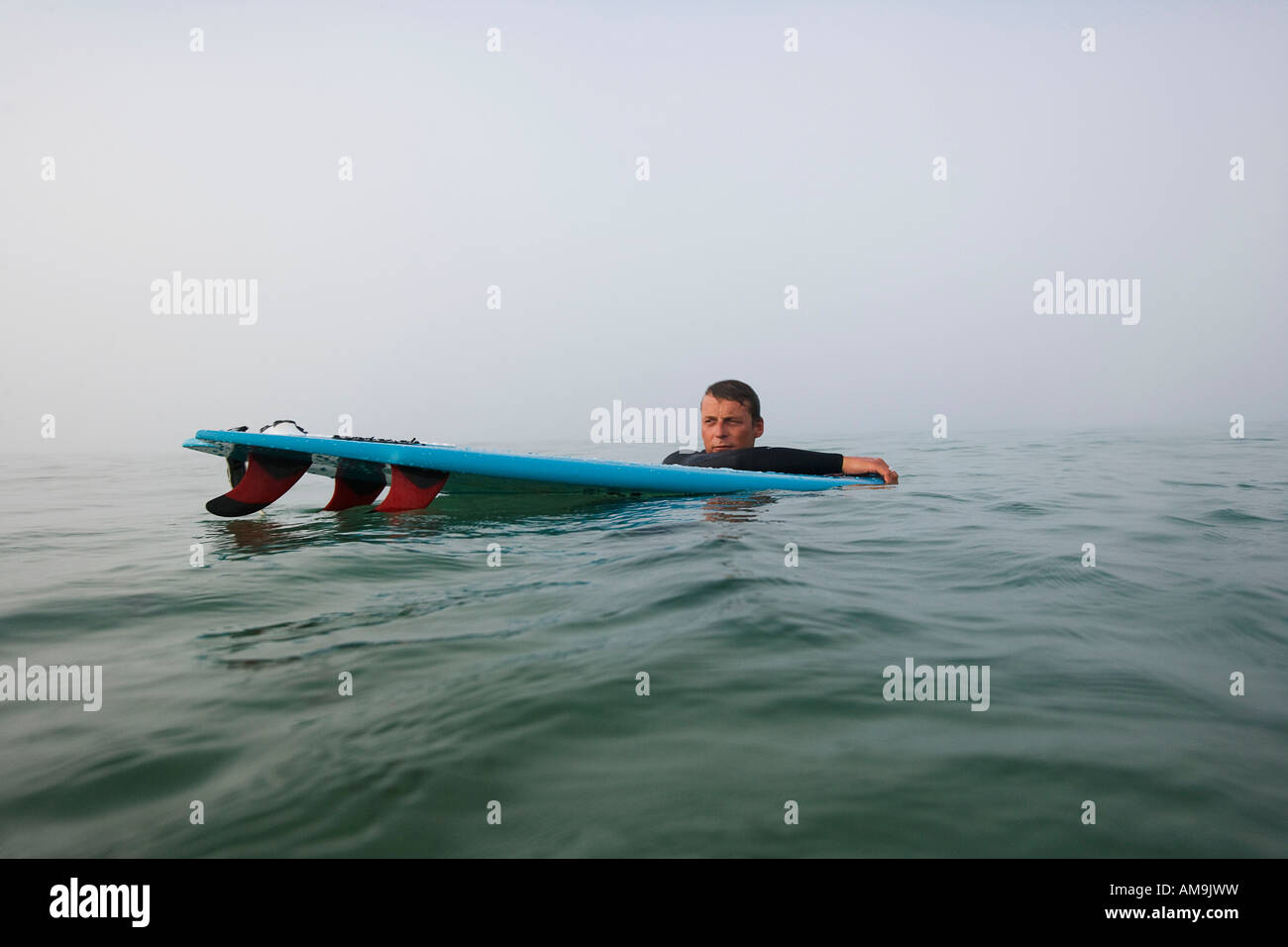 Man floating with surfboard in the water Stock Photo - Alamy