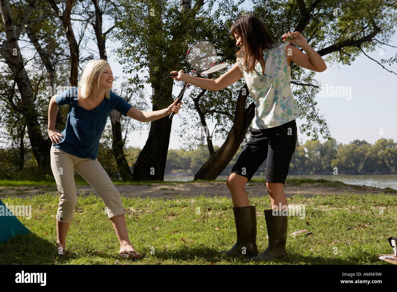 Two women play fighting with badminton racquets and laughing at ...
