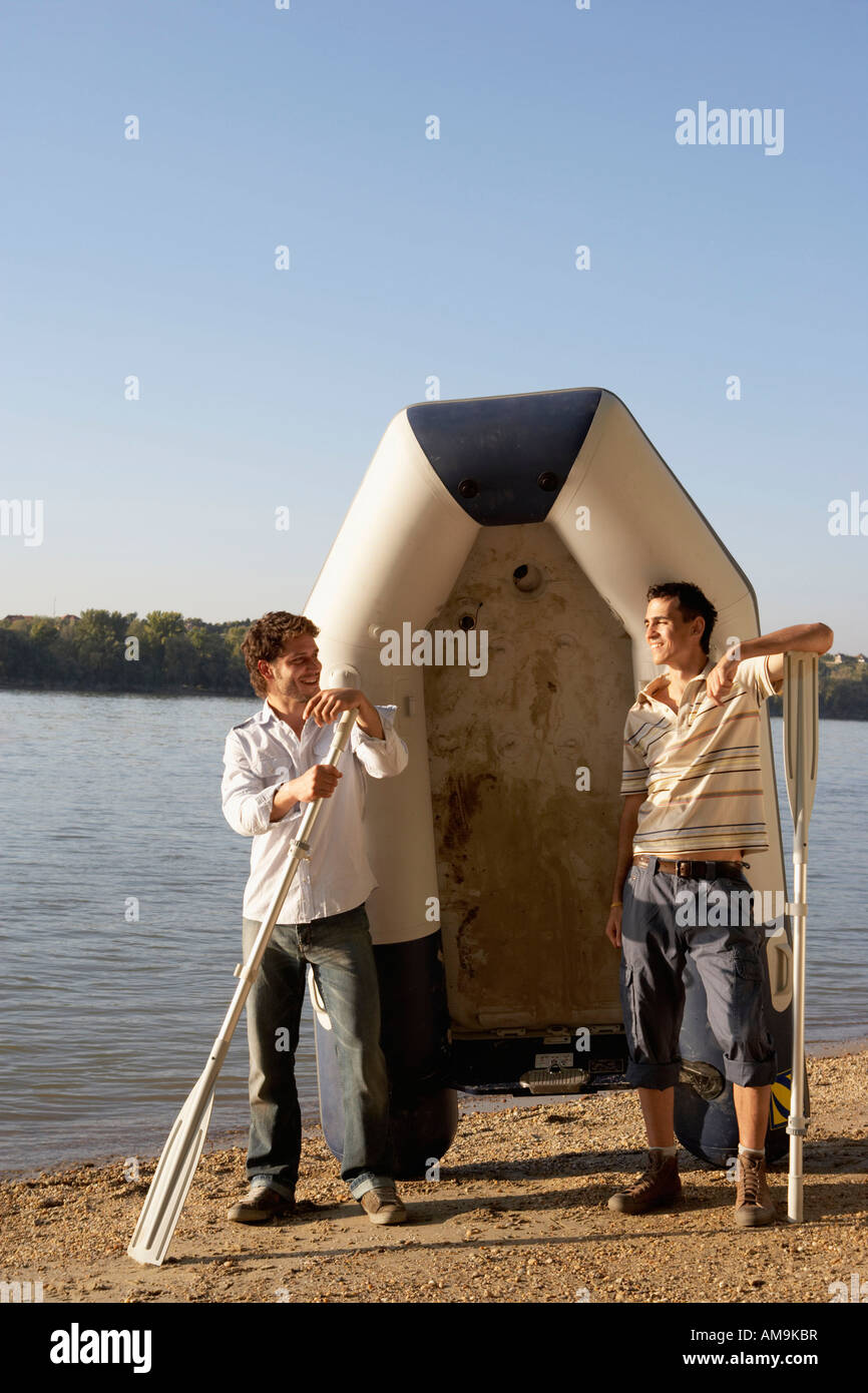 Two men with oars and a raft on a beach smiling Stock Photo - Alamy