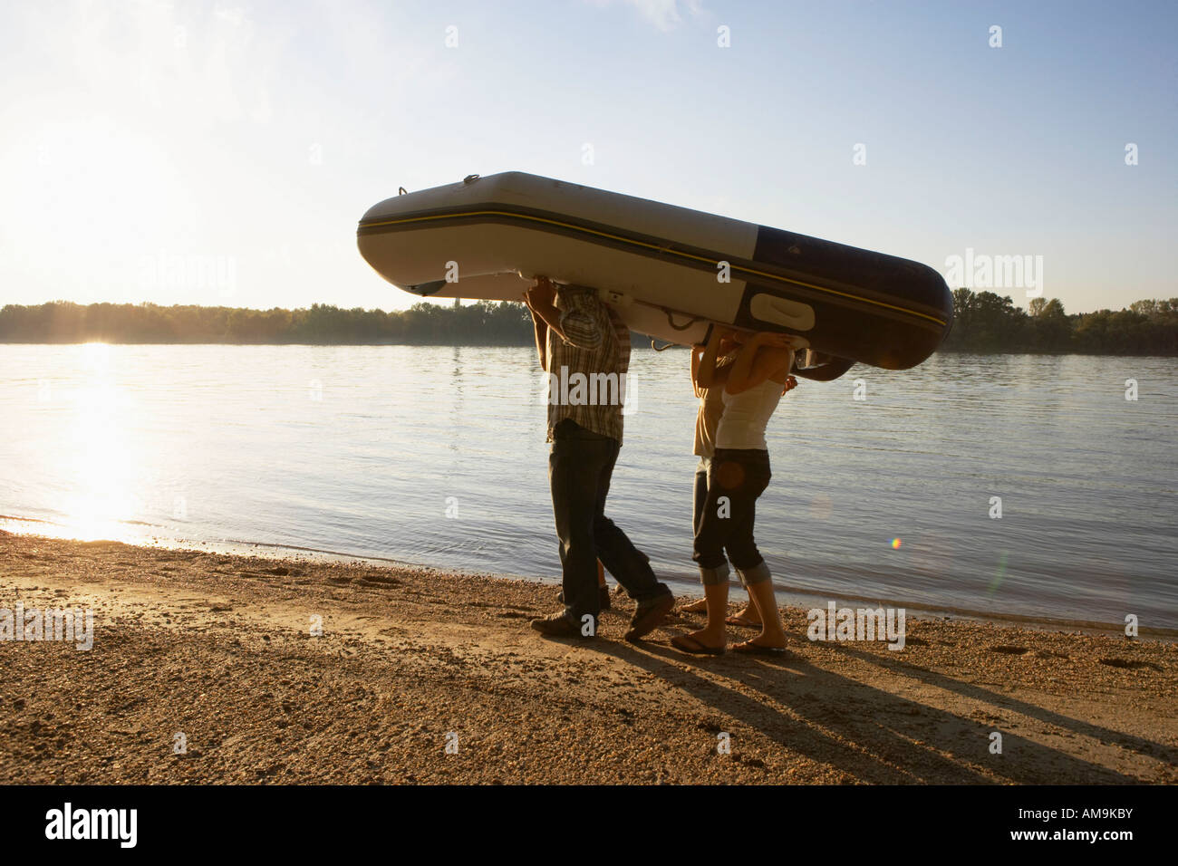 Four friends carrying a raft on a beach Stock Photo - Alamy