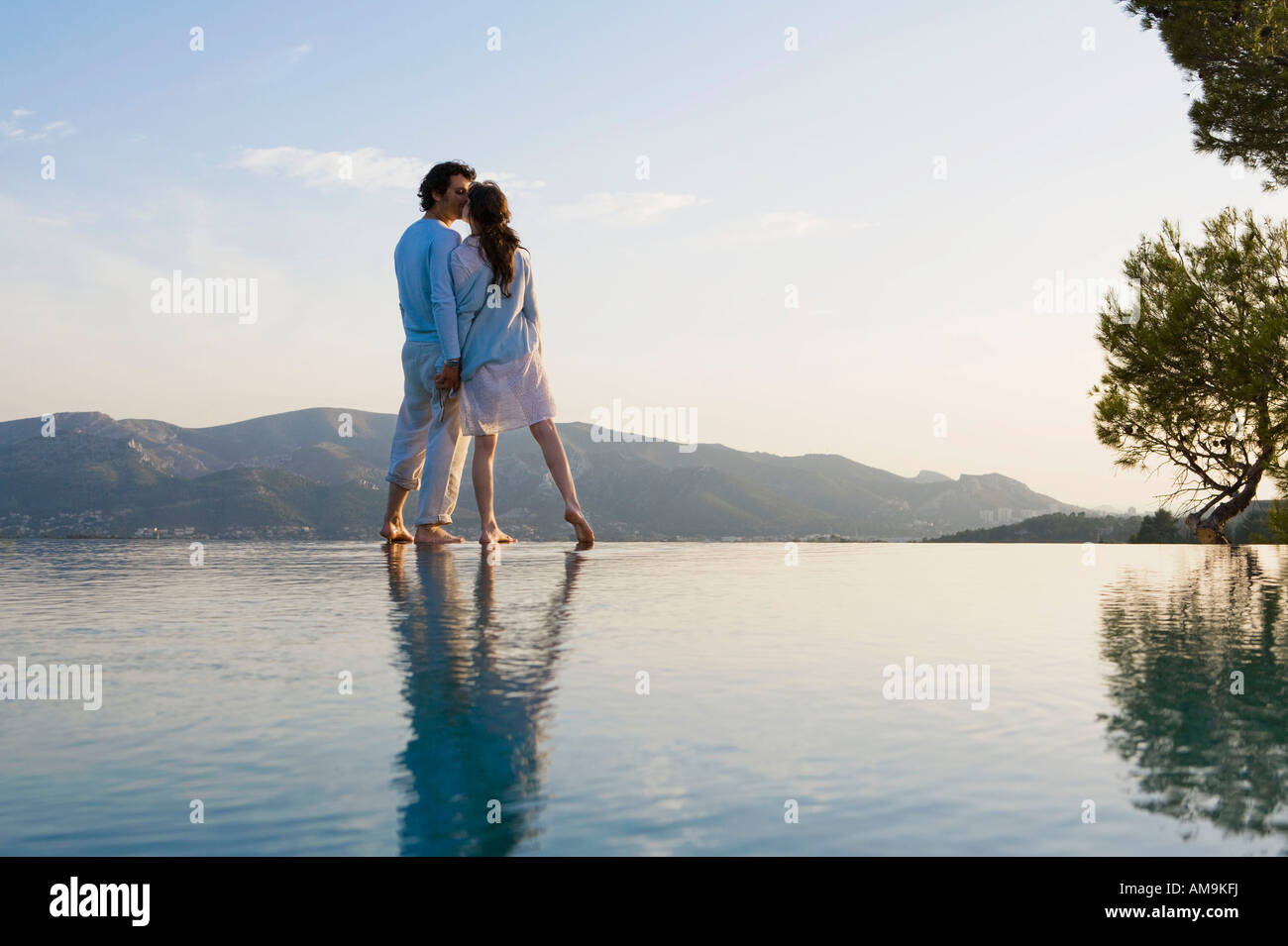 Couple kissing and holding hands by infinity pool Stock Photo - Alamy