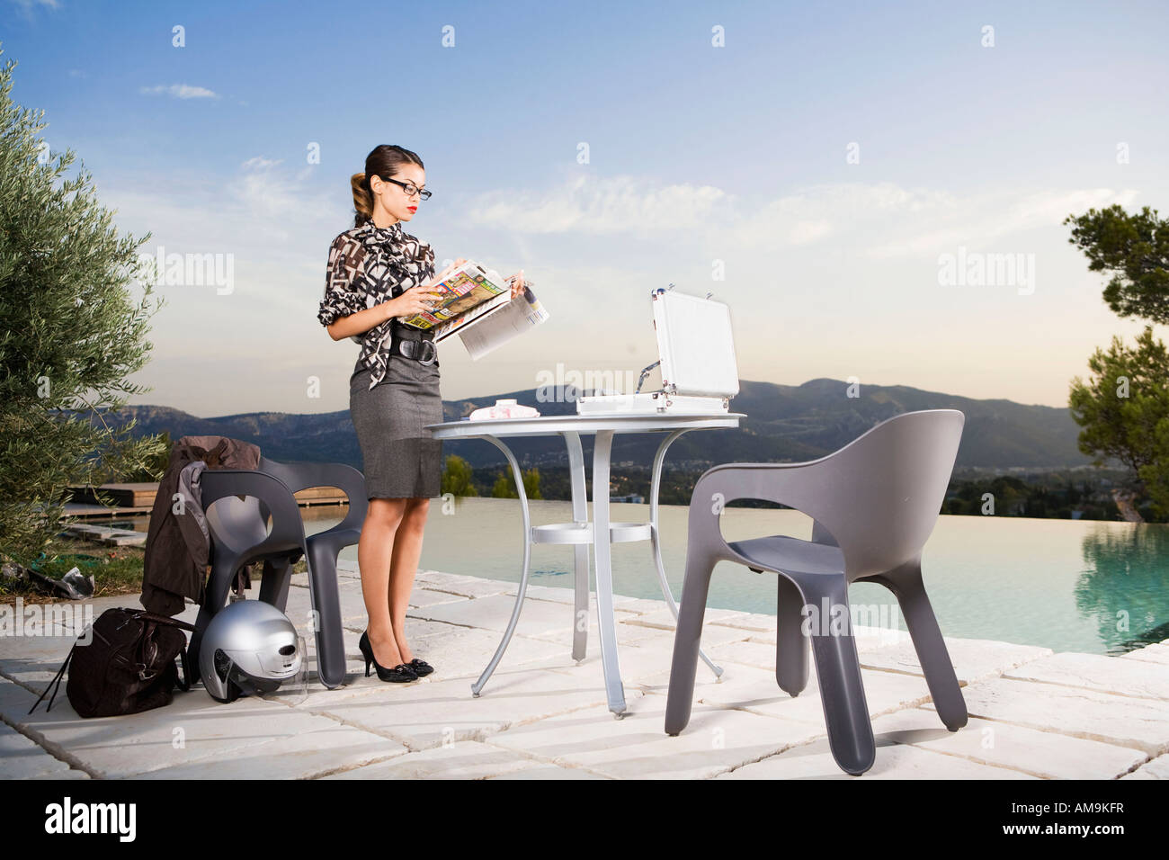 Woman at patio table working by infinity pool Stock Photo - Alamy