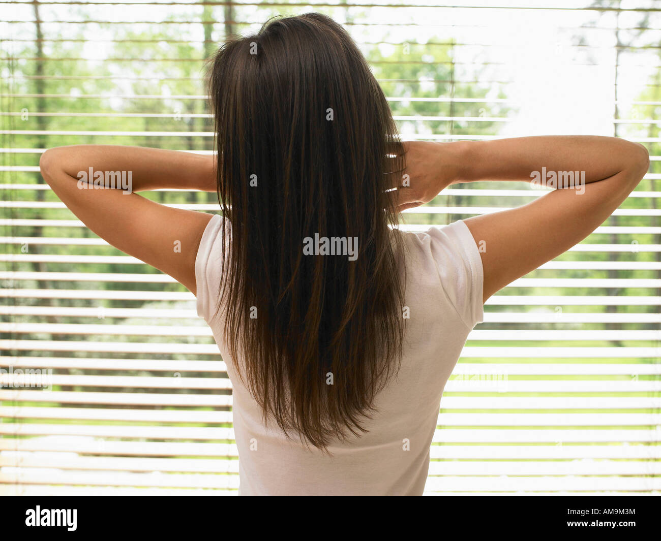 Woman standing by a window stretching Stock Photo - Alamy