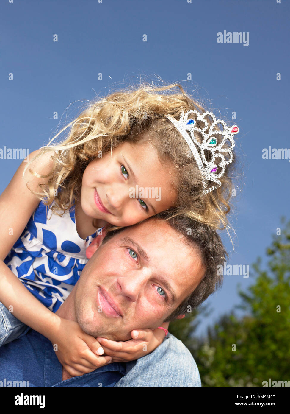Man with smiling young girl wearing tiara on shoulders Stock Photo - Alamy