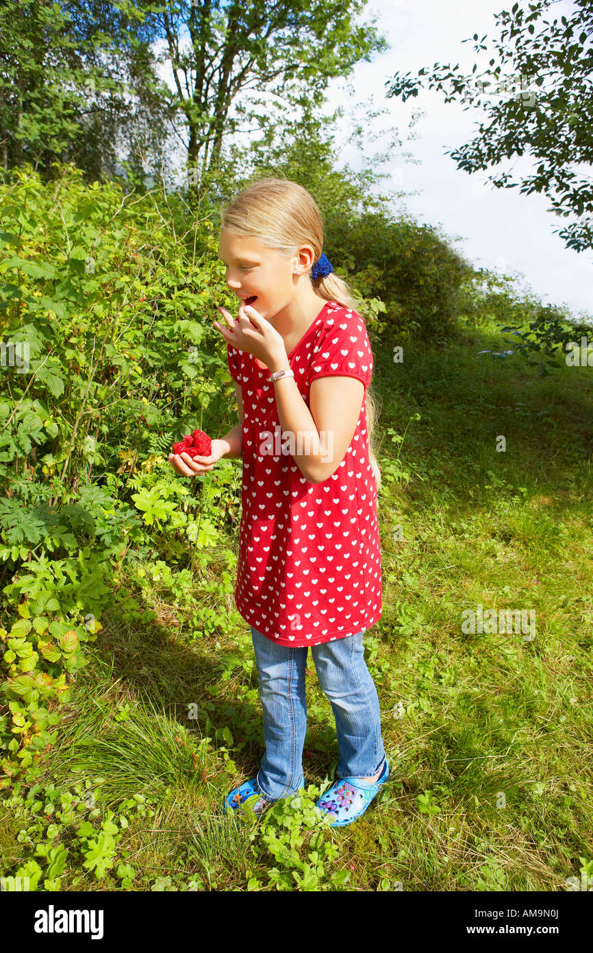 Young girl eating fresh raspberries smiling Stock Photo - Alamy