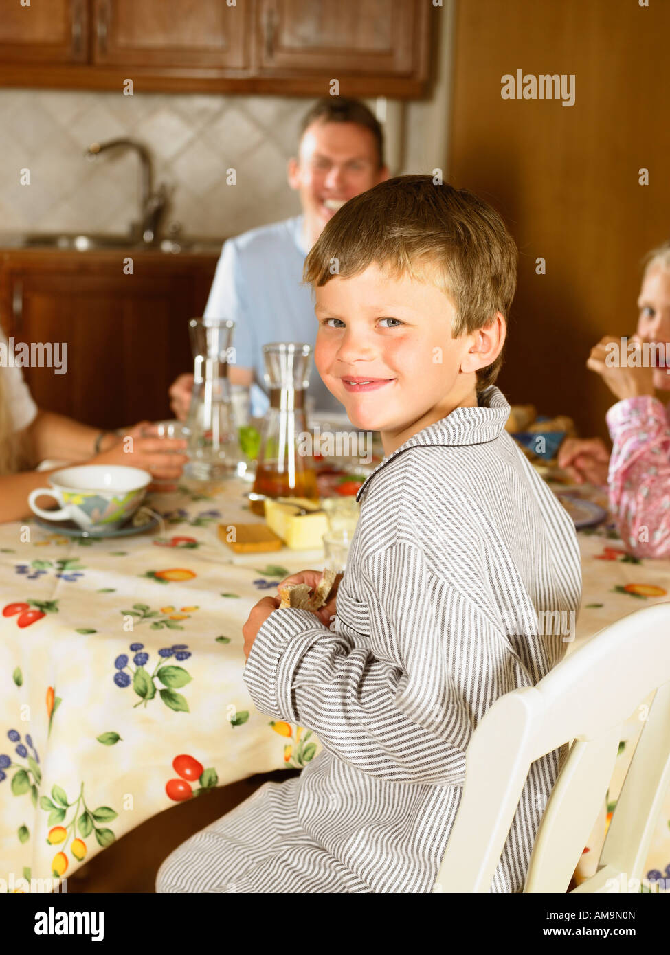 Family sitting at kitchen table eating breakfast smiling Stock Photo ...