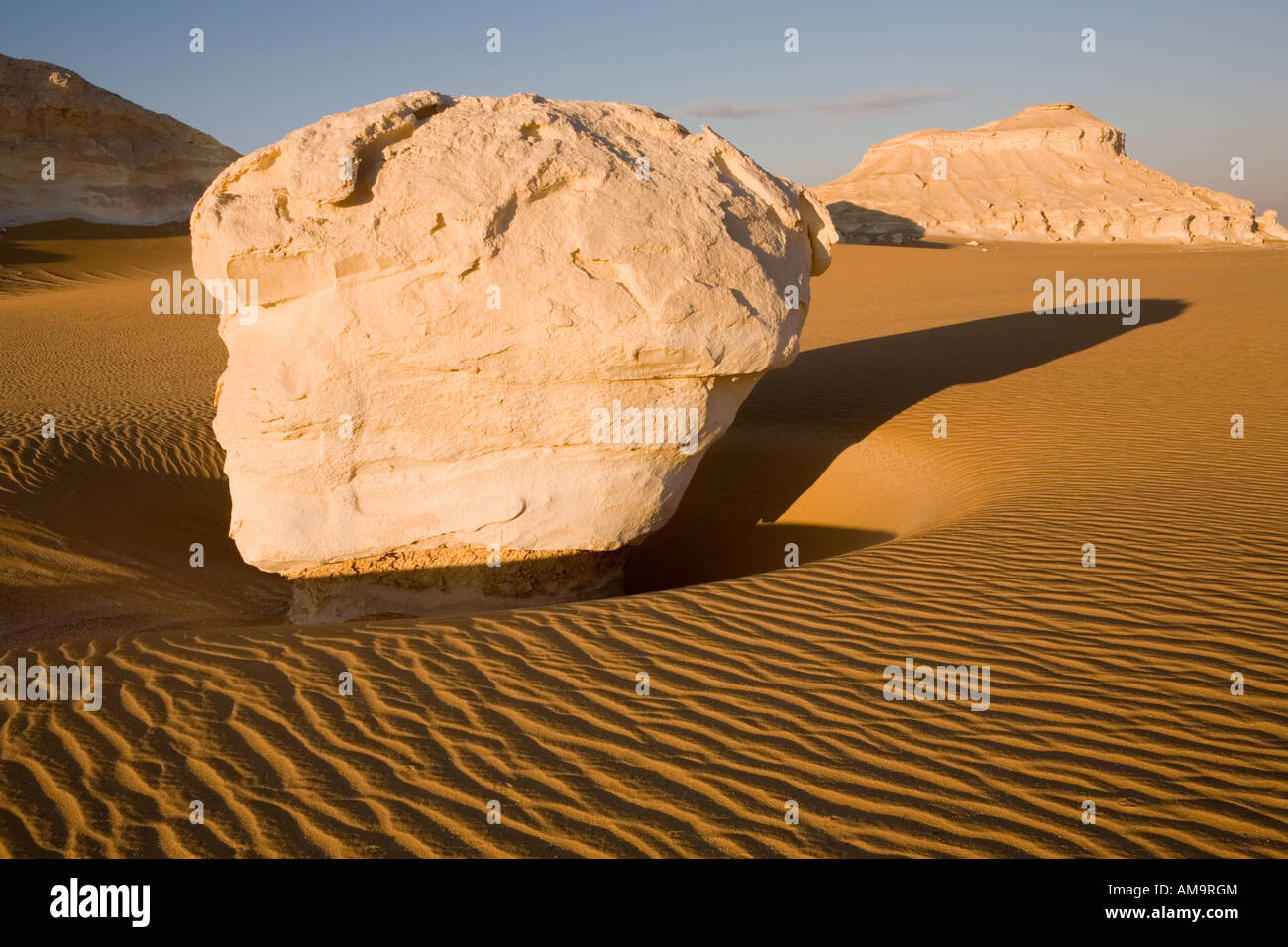 White limestone boulder with rippled sand and long shadow , White ...