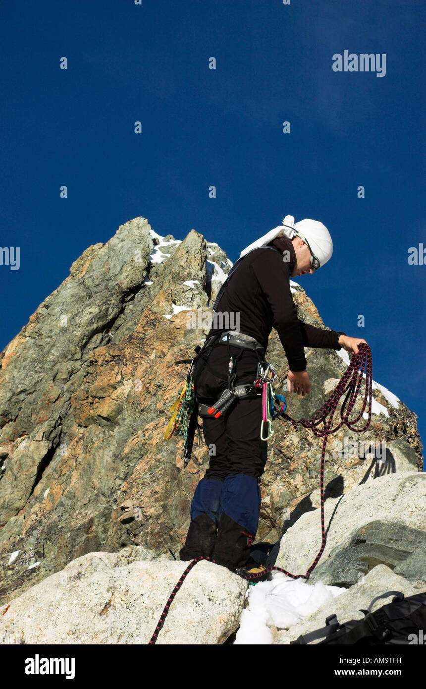 A male mountaineer preparing his rope ready for the climb of the cliff ...