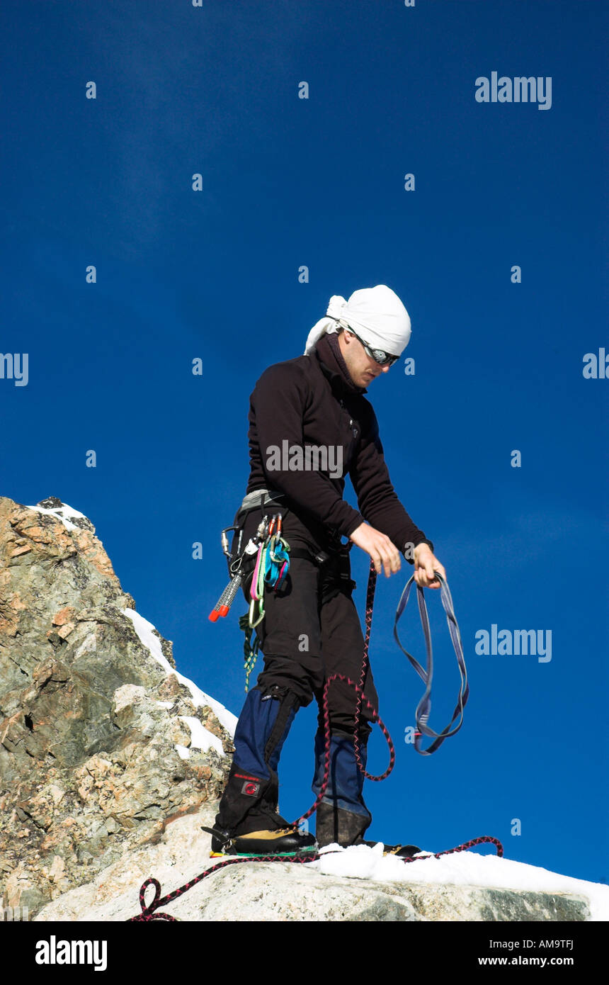A male mountaineer preparing his rope ready for the climb of the cliff ...