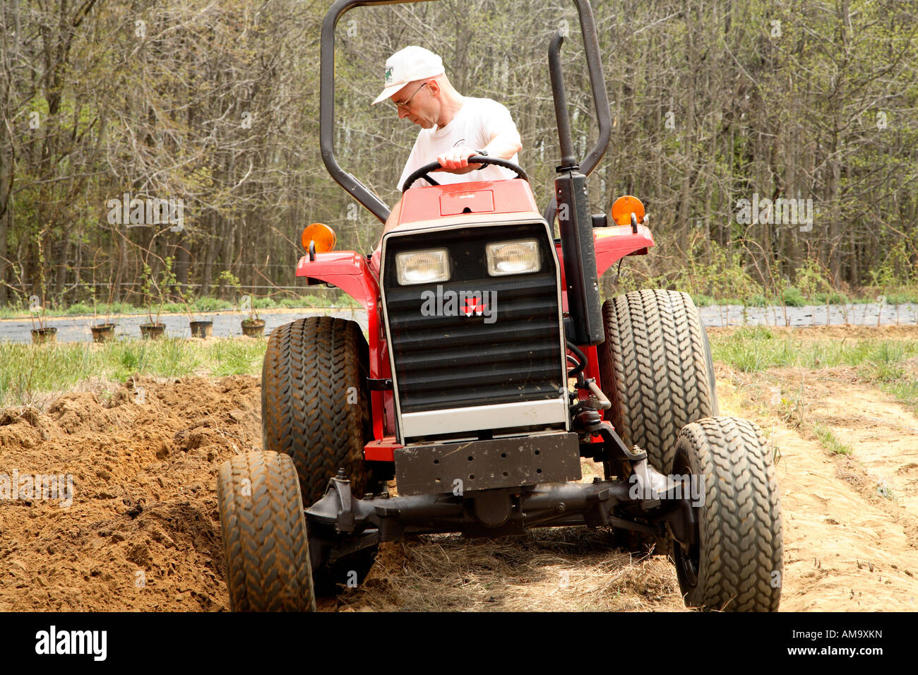 Man driving a small tractor ploughing or plowing field on specialist ...