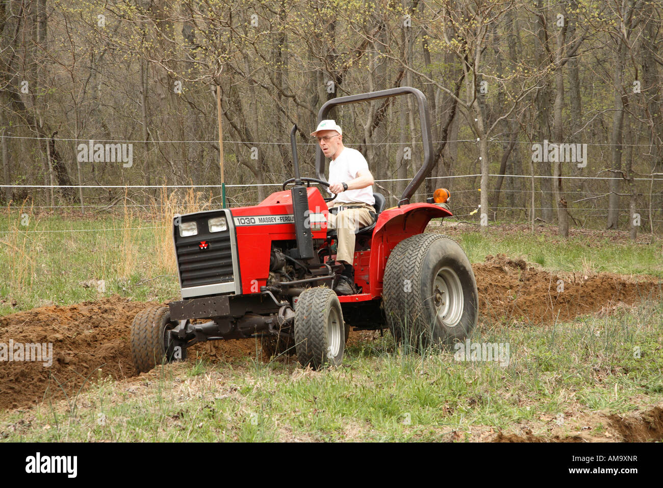 Man on small tractor ploughing up a small piece of fallow land on ...