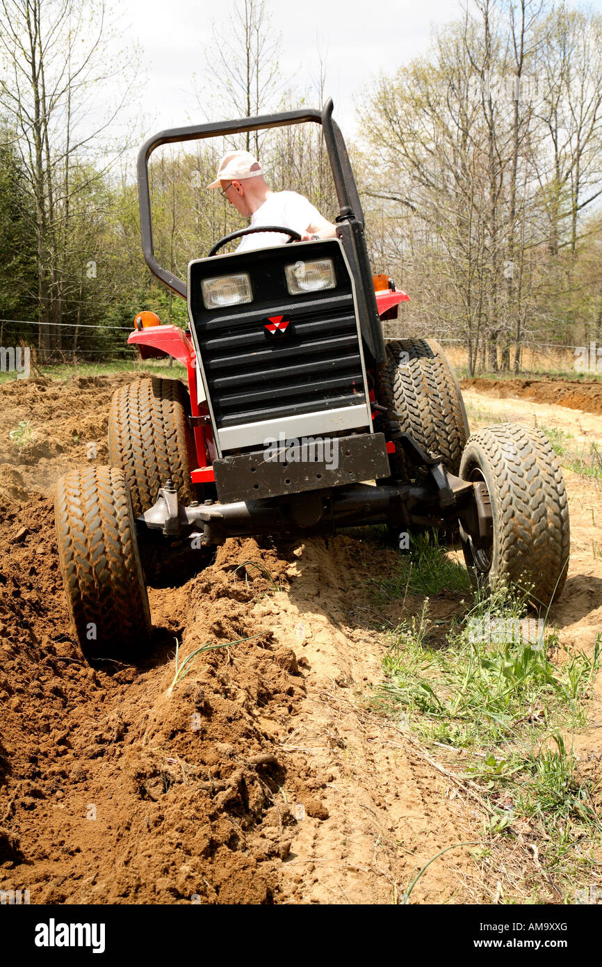 Man driving a small tractor ploughing or plowing field on specialist ...