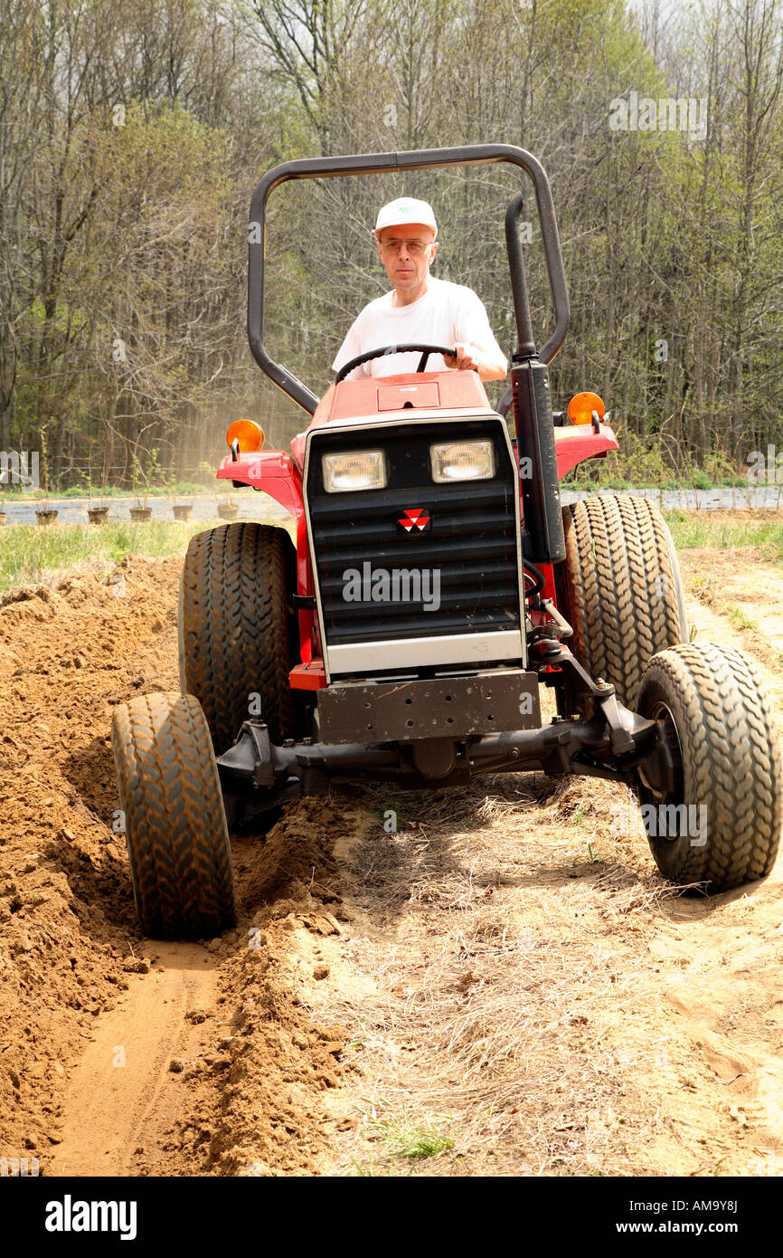 Man driving a small tractor ploughing or plowing field on specialist ...
