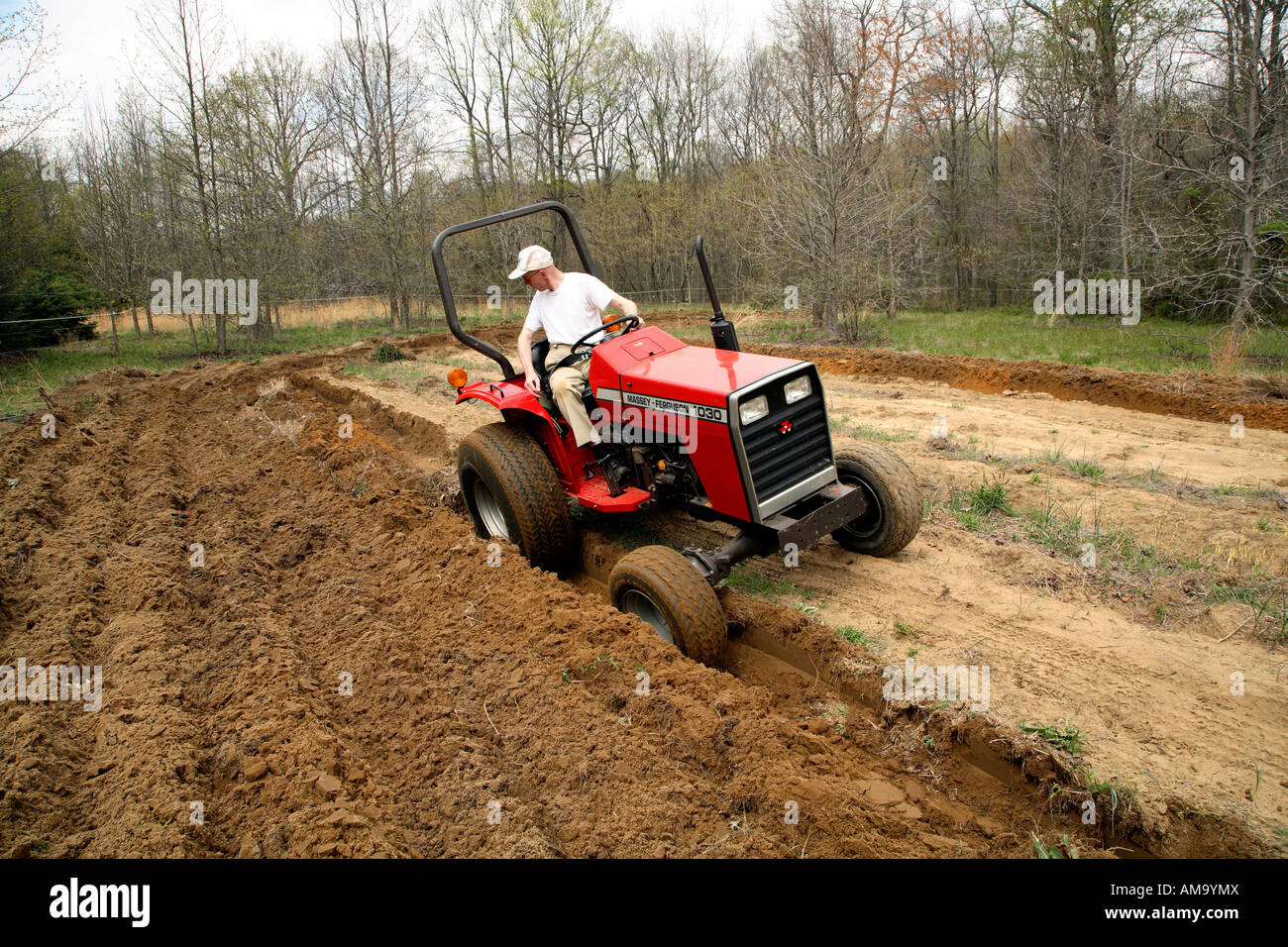 Man driving a small tractor ploughing or plowing field on specialist ...