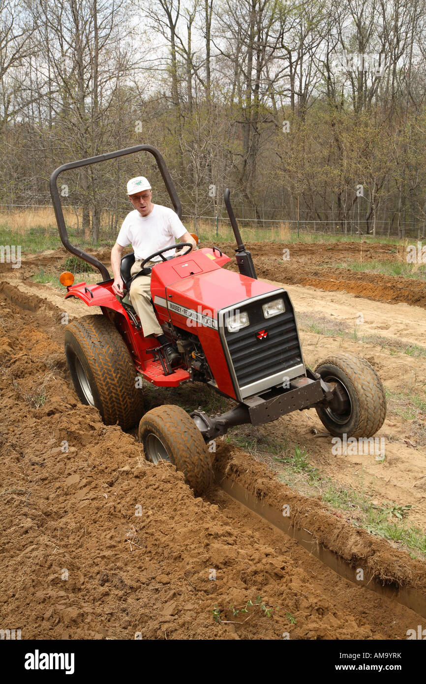 Man driving a small tractor ploughing or plowing field on specialist ...