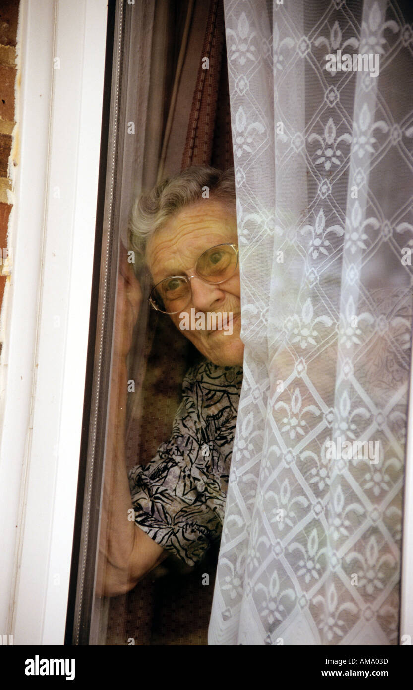 elderly lady looking out of window concerned Stock Photo - Alamy