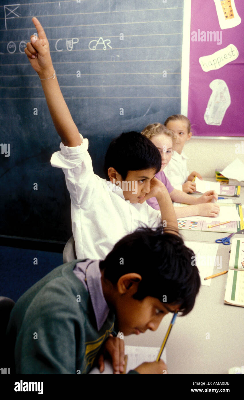 Child raising his hand to answer a question in primary school classroom ...