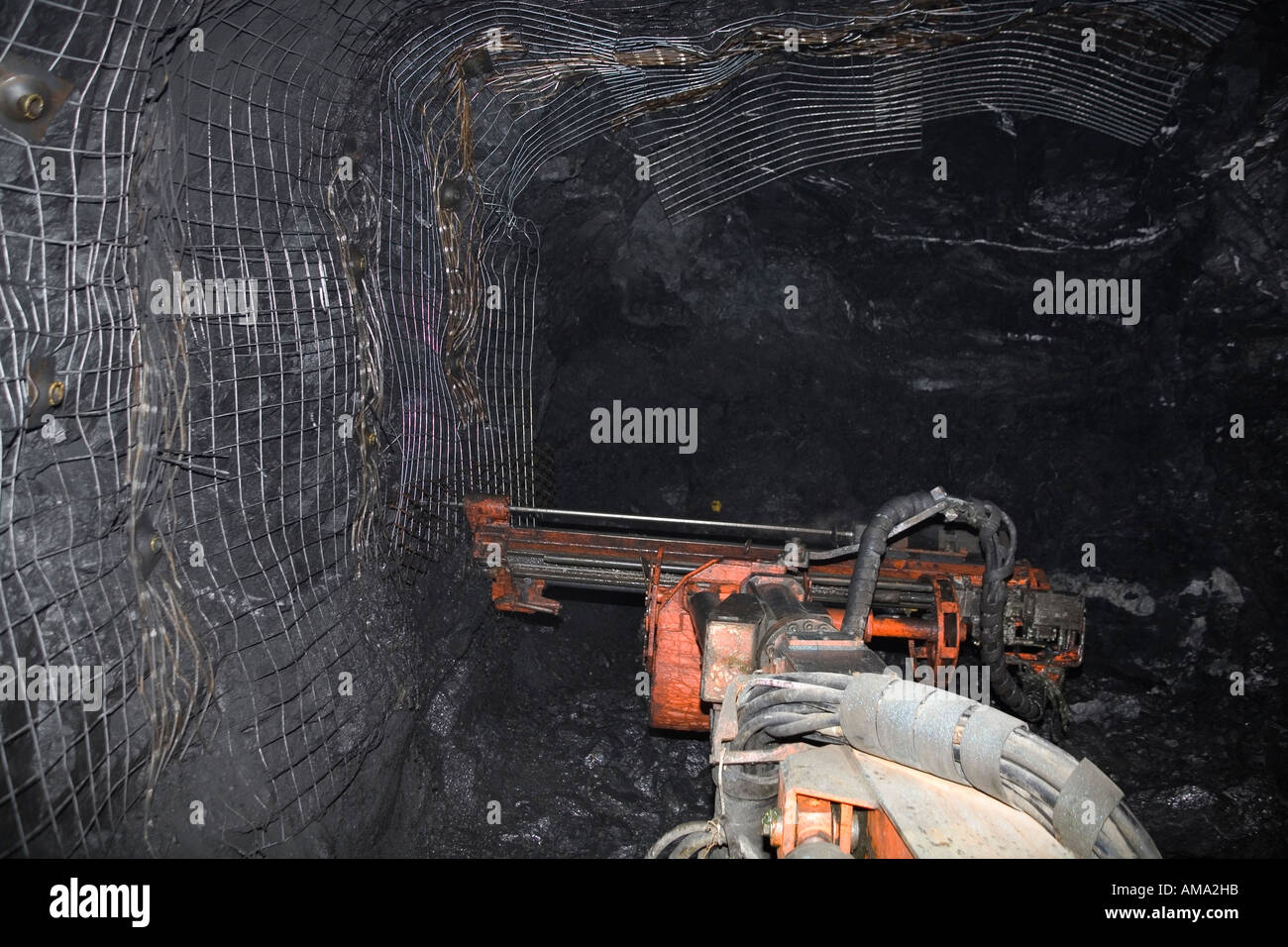 Jumbo mining equipment at stope face placing rock bolts and mesh for ...