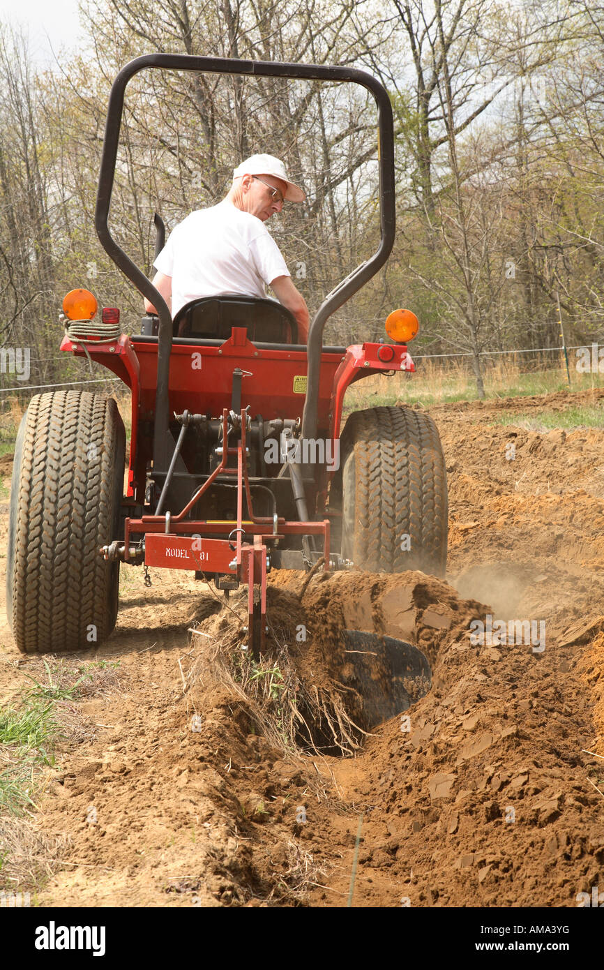 Man driving a small tractor ploughing or plowing field on specialist ...
