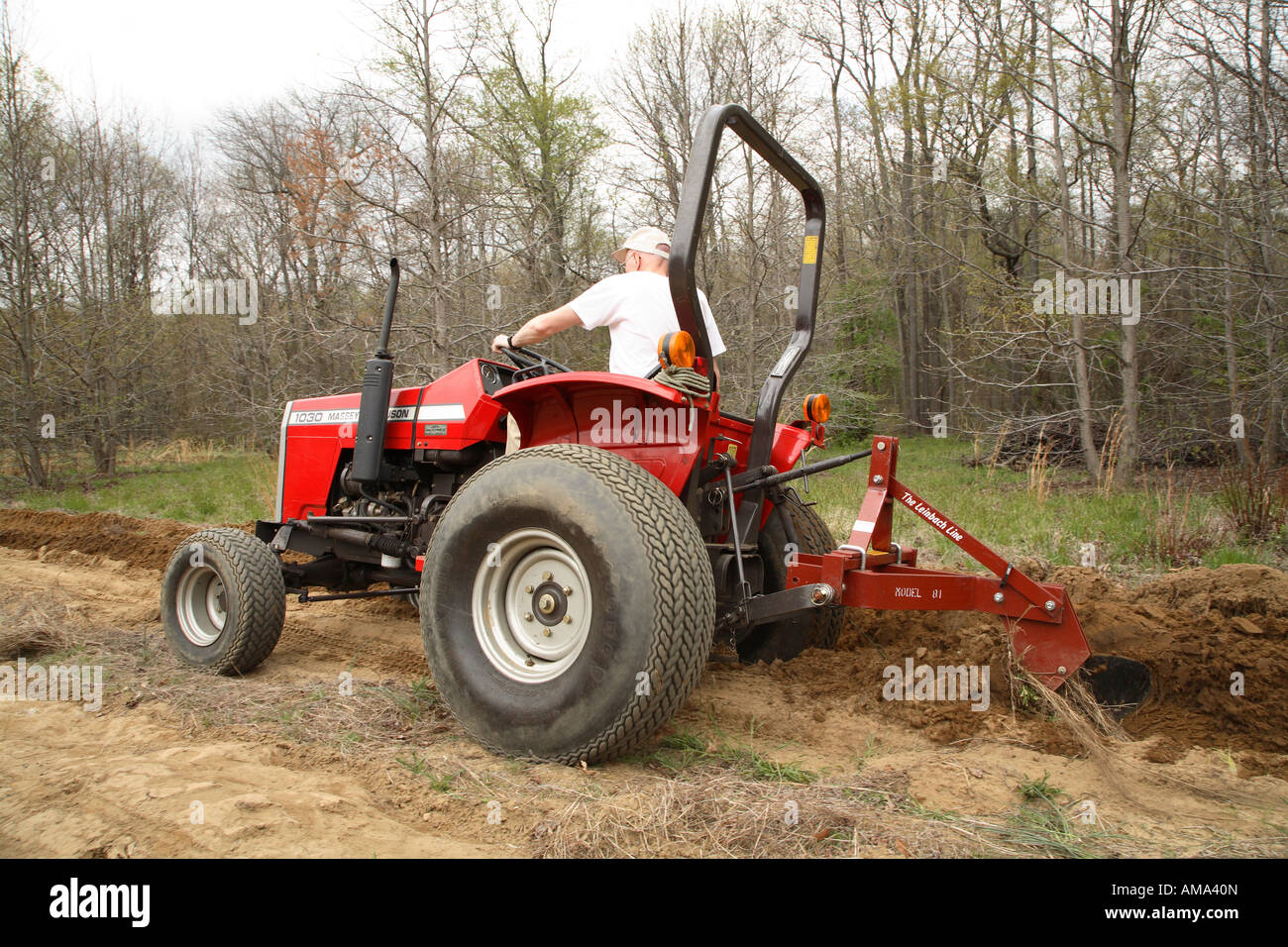 Man driving a small tractor ploughing or plowing field on specialist ...
