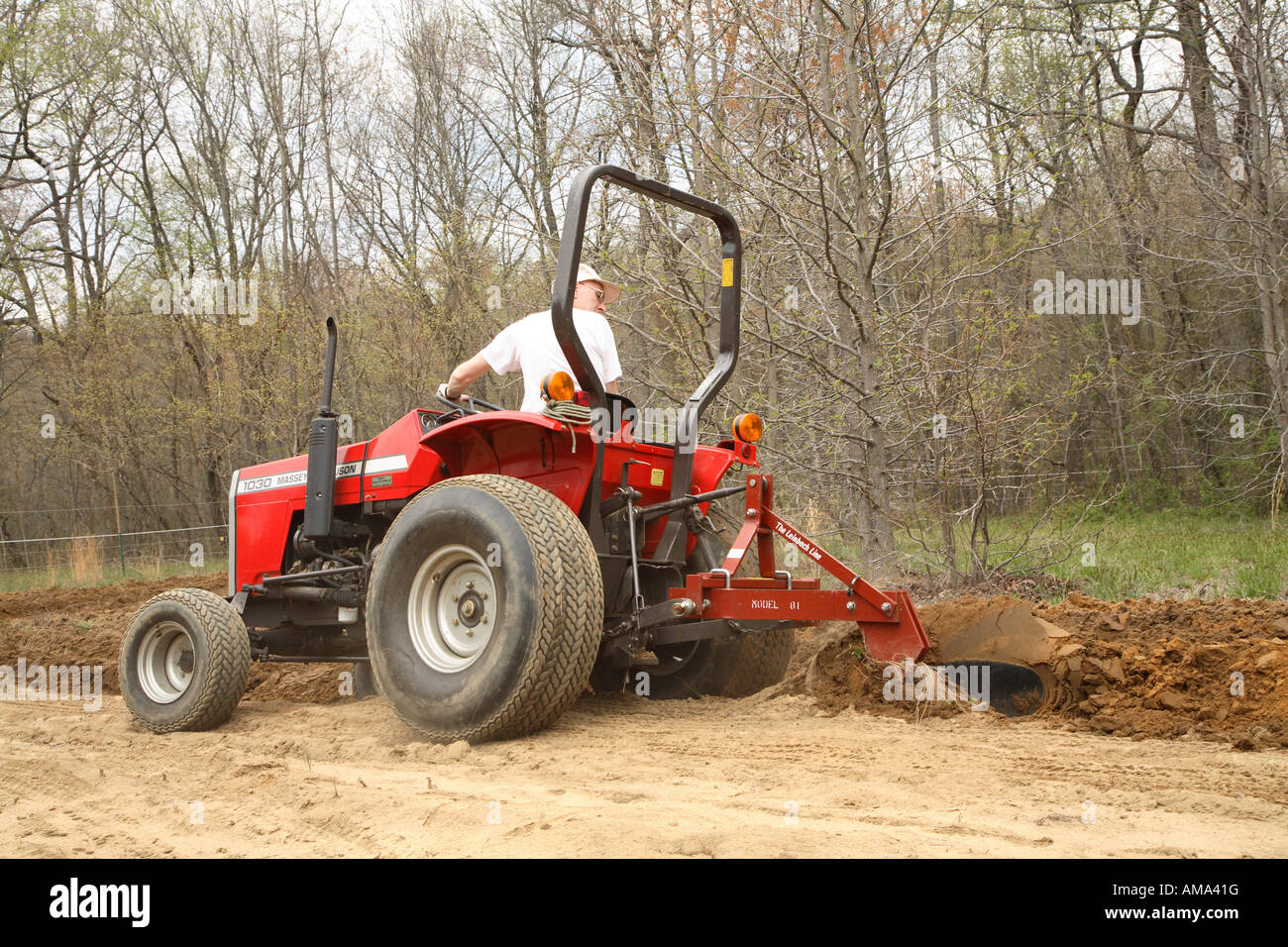 Man driving a small tractor ploughing or plowing field on specialist ...