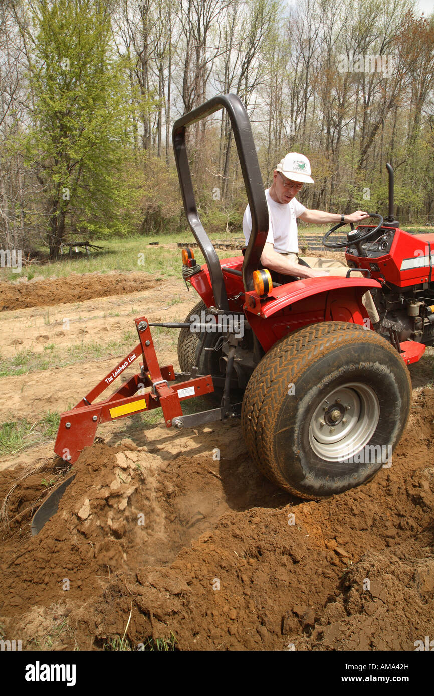 Man driving a small tractor ploughing or plowing field on specialist ...