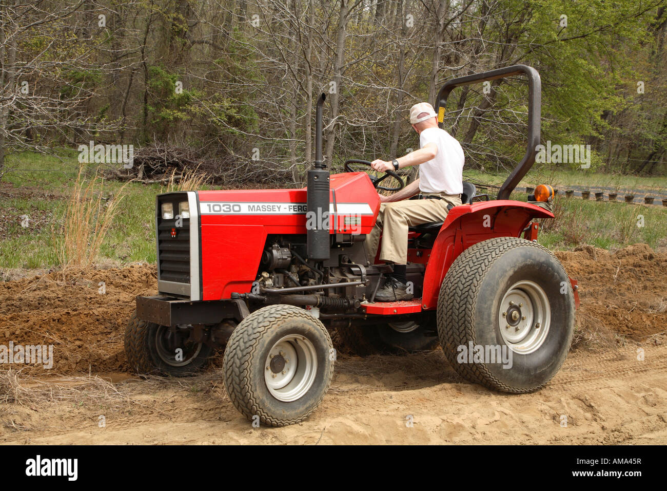 Man driving a small tractor ploughing or plowing field on specialist ...