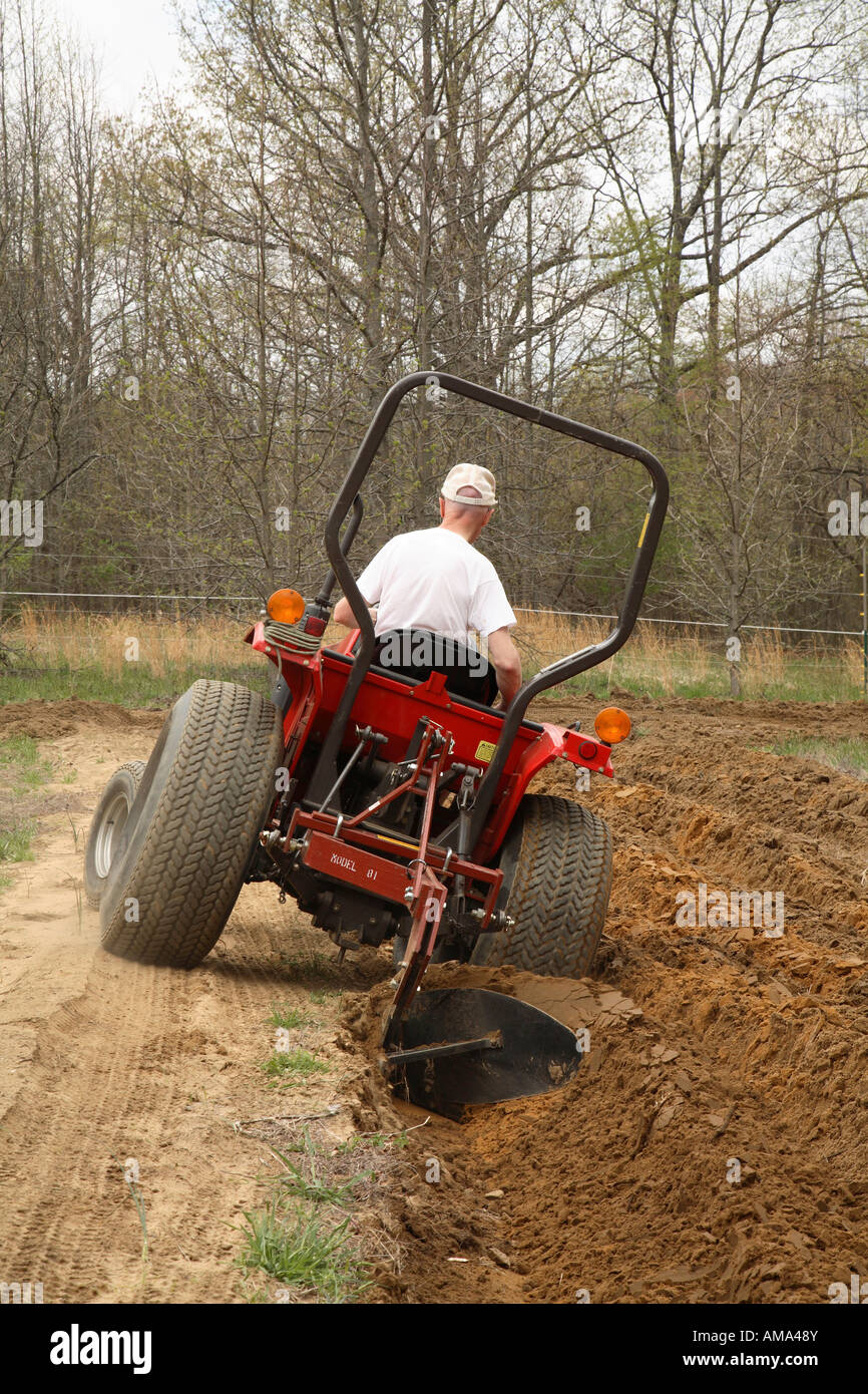 Man driving a small tractor ploughing or plowing field on specialist ...