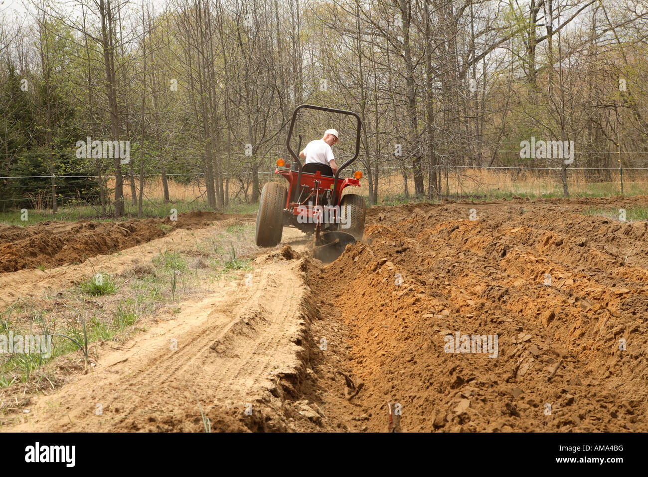 Man driving a small tractor ploughing or plowing field on specialist ...