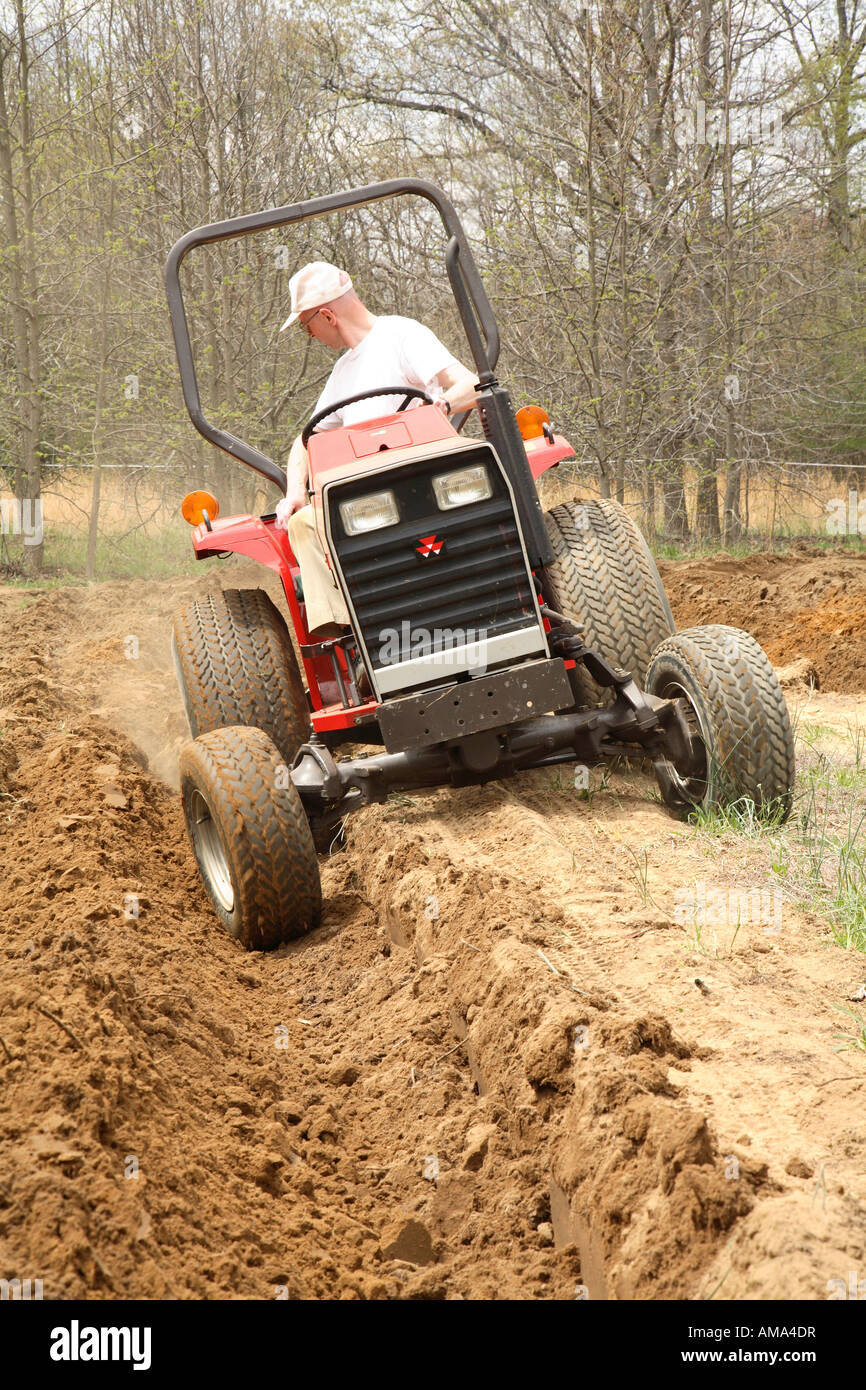 Man driving a small tractor ploughing or plowing field on specialist ...