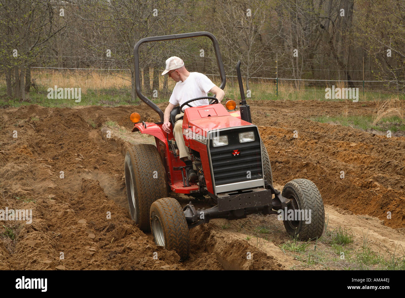 Man driving a small tractor ploughing or plowing field on specialist ...