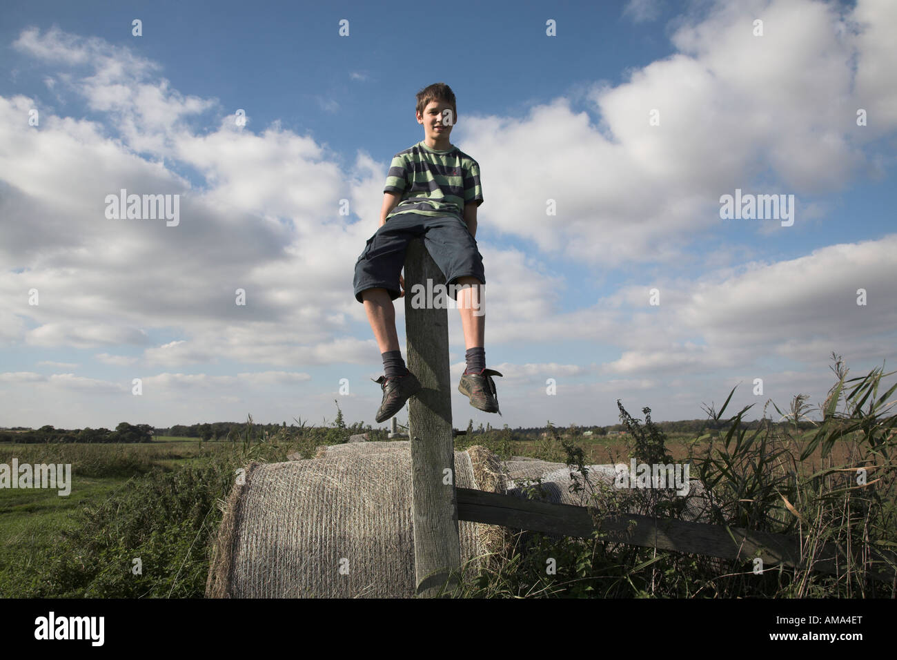 Young teenage boy sitting on post in countryside Stock Photo - Alamy