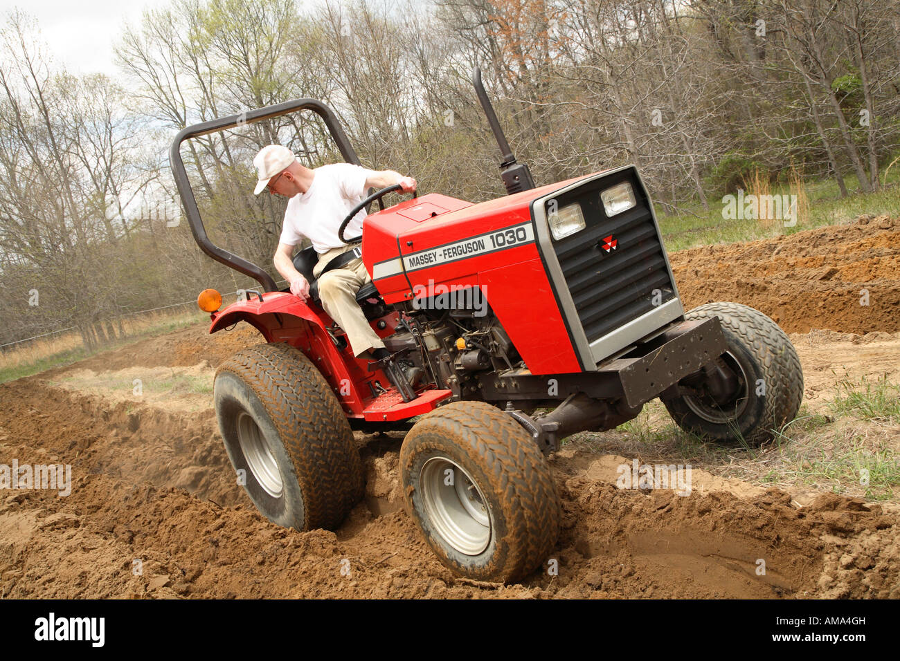 Man driving a small tractor ploughing or plowing field on specialist ...